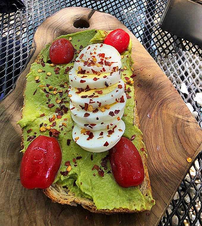 This avocado toast takes flight with perfectly sliced eggs, vibrant tomatoes, and red pepper flakes &ndash; simple ingredients elevated to first-class status.