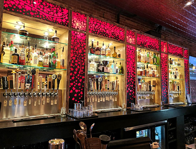Behind this bar, craft beer taps and backlit bottles dance against cherry blossom-inspired panels. Pure cocktail theater!