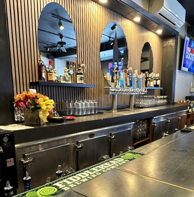 Sleek mirrors and warm wood paneling frame this inviting bar, where craft beers and conversations flow freely.