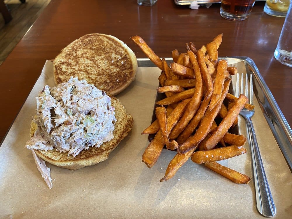 Behold the golden perfection: sweet potato fries paired with a chicken salad sandwich, proving that simple combinations create the most memorable meals.