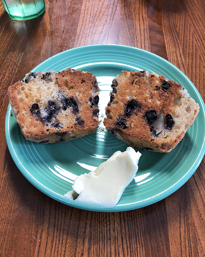 Blueberry muffin perfection split and buttered, proving that sometimes simple pleasures require nothing more than fruit, flour, and someone who knows what they're doing in the kitchen.