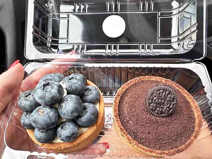 Nature's candy meets culinary artistry: plump blueberries crown a perfect tart while an Oreo stands sentinel atop its chocolate kingdom.
