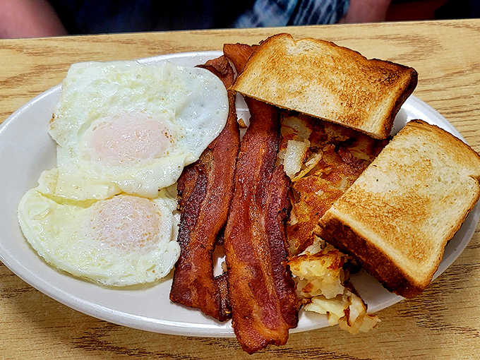 Breakfast perfection on a plate: golden eggs, crispy bacon, and home fries that strike the ideal balance between crisp edges and tender centers.