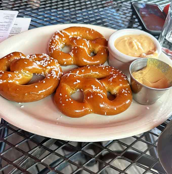 Golden Bavarian pretzels arrive like edible sunshine, their salt crystals sparkling with the promise of pure deliciousness ahead.