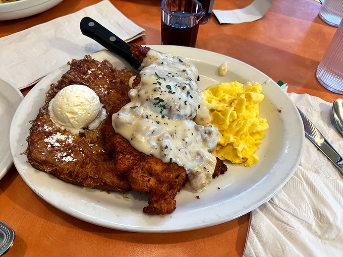Behold the legendary chicken fried chicken! Crispy, golden perfection smothered in country gravy alongside fluffy eggs &ndash; comfort food elevated to art form.