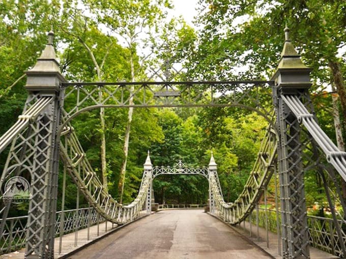 The bridge's Victorian-inspired design creates a striking silhouette against the forest backdrop, a perfect marriage of human craftsmanship and natural beauty.