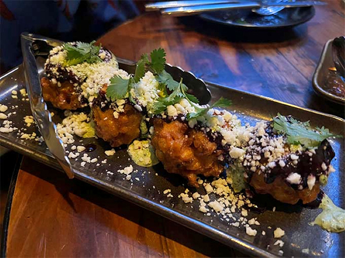 Golden corn fritters that crackle with each bite, topped with crumbled cheese and herbs &ndash; proof that humble ingredients can achieve greatness.