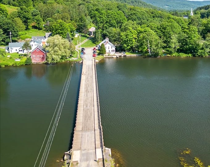 Aerial view reveals the Floating Bridge's impressive 321-foot span, a wooden ribbon stretching across Sunset Lake's glassy surface.
