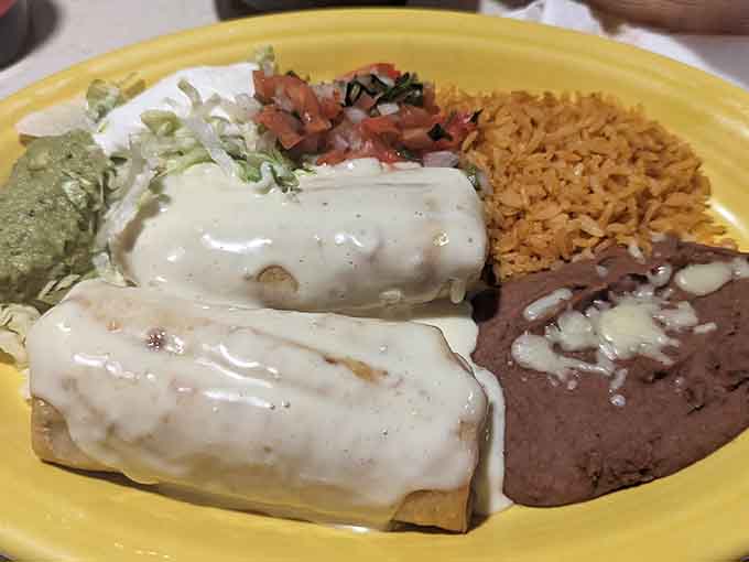 These golden chimichangas arrive smothered in cheese sauce, flanked by rice and beans that are anything but afterthoughts.