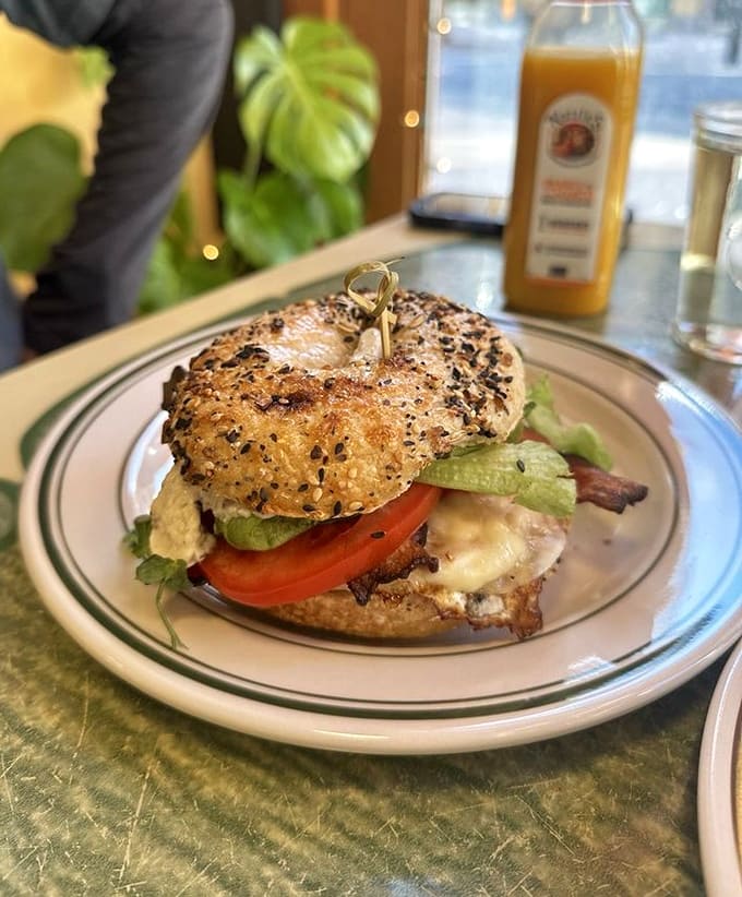 Behold the breakfast sandwich in all its glory: bacon, egg, cheese, and fresh veggies on a sesame bagel that's pure perfection.