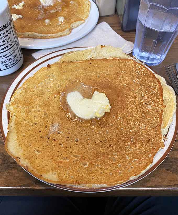 Behold the pancake that launched a thousand return visits, golden and glorious with a pat of butter melting into pure breakfast bliss.