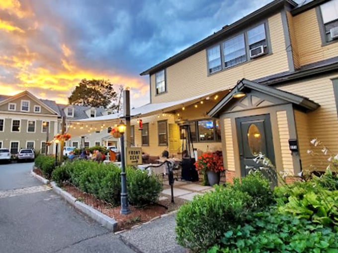 The historic building stands proudly against a dramatic sunset, its wraparound porch promising comfort and hospitality in equal measure.
