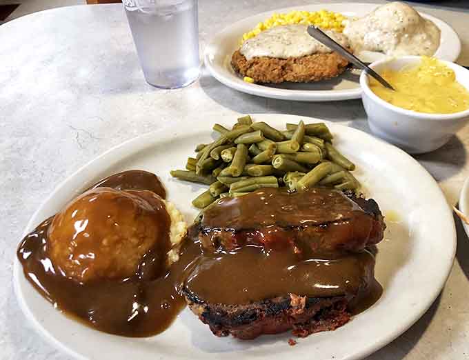 Meatloaf smothered in rich brown gravy, served with green beans and mashed potatoes &ndash; comfort food that hugs you from the inside.