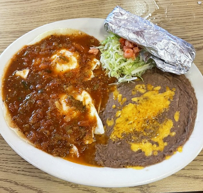 Huevos rancheros arrive swimming in rich, spicy sauce alongside perfectly refried beans topped with melted cheese &ndash; breakfast nirvana on a plate.