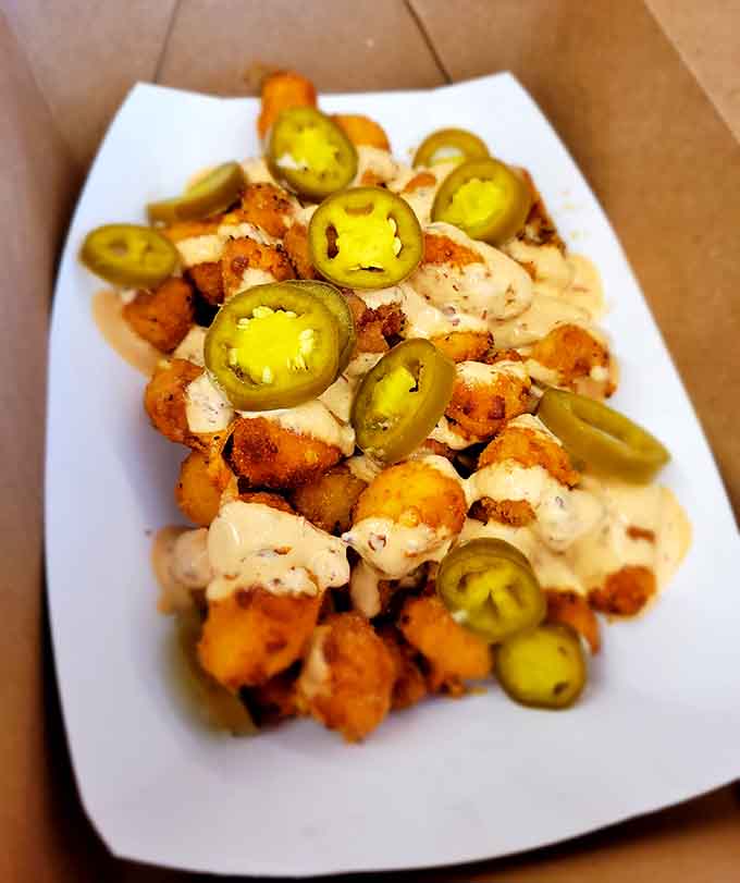 Golden cheese curds topped with jalape&ntilde;os and drizzled with sauce, because sometimes perfection needs a little extra something.