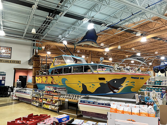 A full-sized boat sits indoors like it's perfectly normal, painted cheerfully and ready for absolutely no voyage.