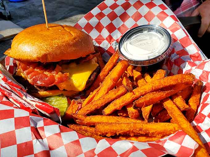 That bacon cheeseburger paired with sweet potato fries represents everything right about American dining, stacked high and ready to impress.