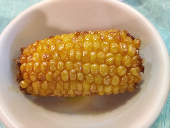 Behold the golden glory of deep-fried corn on the cob, glistening in butter like edible sunshine in a bowl.