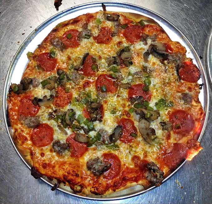 Pepperoni, mushrooms, and green peppers unite in crispy, thin-crust harmony, like the pizza version of a perfectly balanced barbershop quartet.