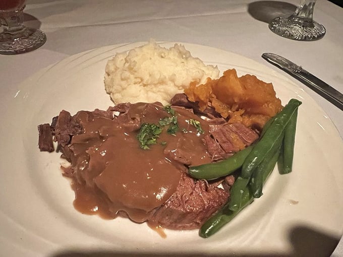 Behold the star of the show &ndash; tender pot roast swimming in rich ale gravy, accompanied by creamy mashed potatoes and vibrant green beans.