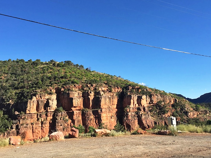 Layered cliffs tell Earth's story in vibrant red chapters, each stratum representing millions of years of geological drama.