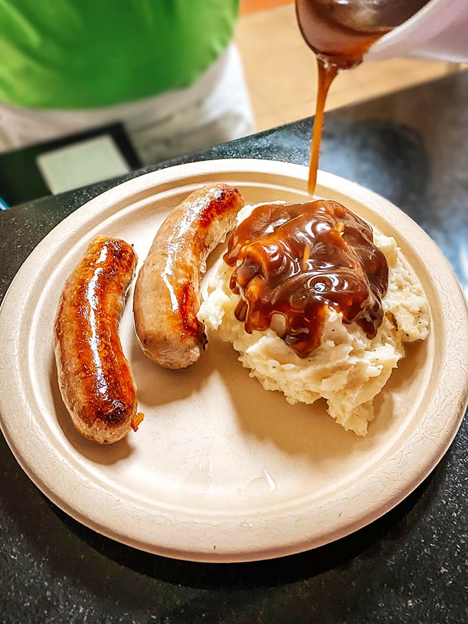 Bangers and mash done right &ndash; plump sausages nestled on creamy potato clouds, all swimming in gravy rich enough to make the Queen herself nod approvingly.