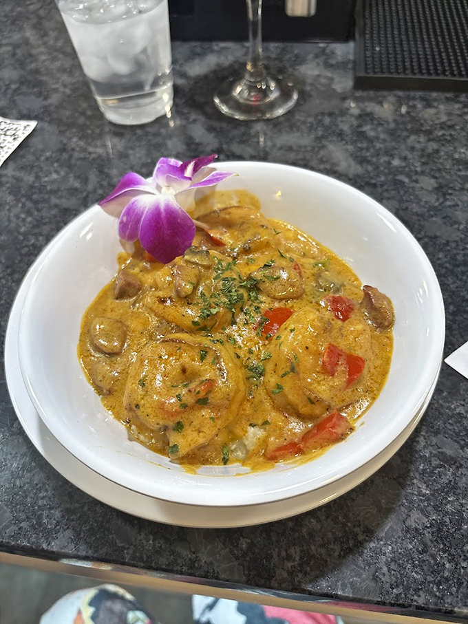This isn't just shrimp and grits; it's a revelation in a bowl. Plump shrimp swimming in creamy sauce atop velvety grits, garnished with a delicate orchid.