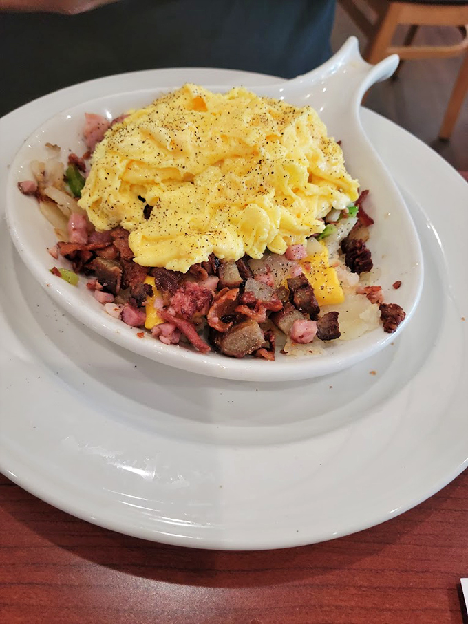 A mountain of breakfast goodness where eggs, meat, and potatoes unite in perfect harmony.