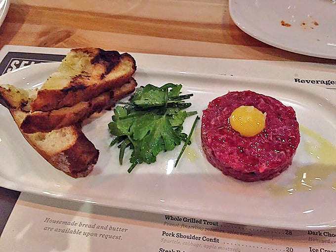 Steak Tartare with Quail Egg: Ruby-red beef crowned with golden yolk royalty. This isn't just raw meat &ndash; it's a textural symphony waiting for your fork to conduct.
