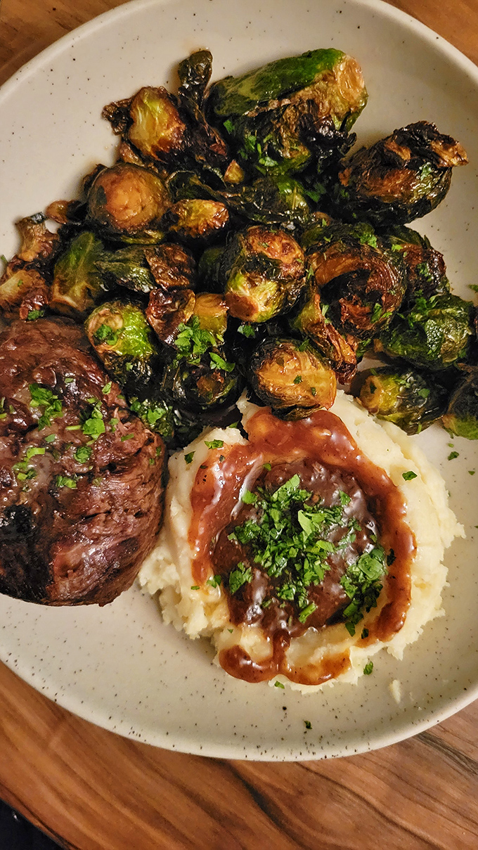 A perfect trifecta: tender filet mignon, creamy mashed potatoes, and Brussels sprouts caramelized to sweet-savory perfection.