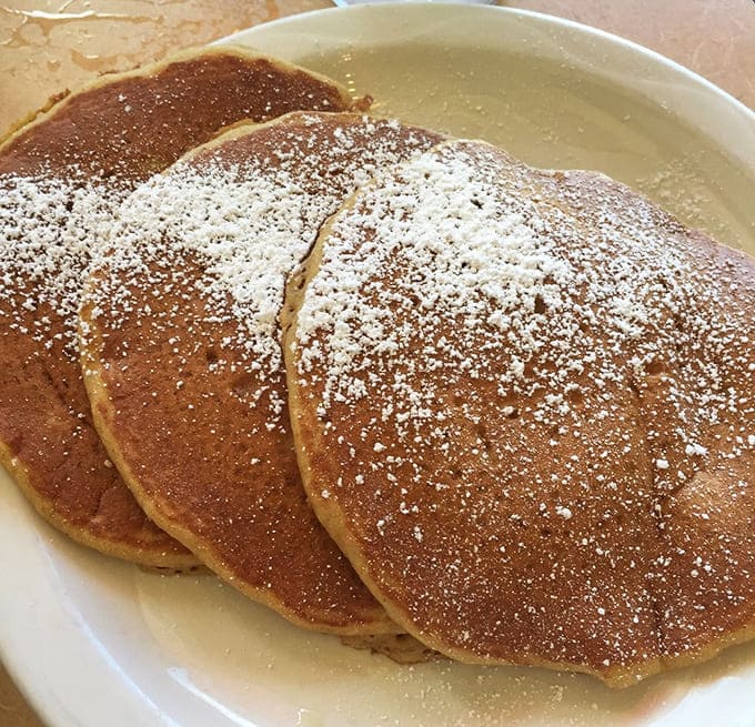 Three golden rounds of pumpkin perfection, dusted with powdered sugar like fresh autumn snow on harvest fields.