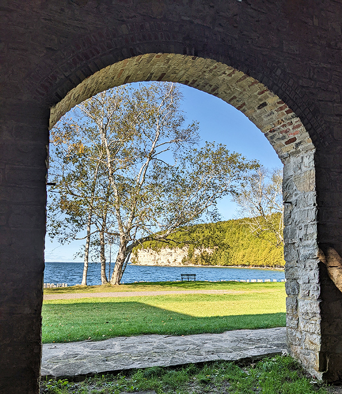 Peering through this stone archway reveals a postcard-perfect view of Snail Shell Harbor, framed like a living painting of Michigan's natural beauty.