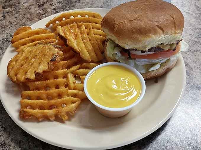 Waffle fries with cheese and a perfectly constructed burger: this is what food happiness looks like on a sunny afternoon.