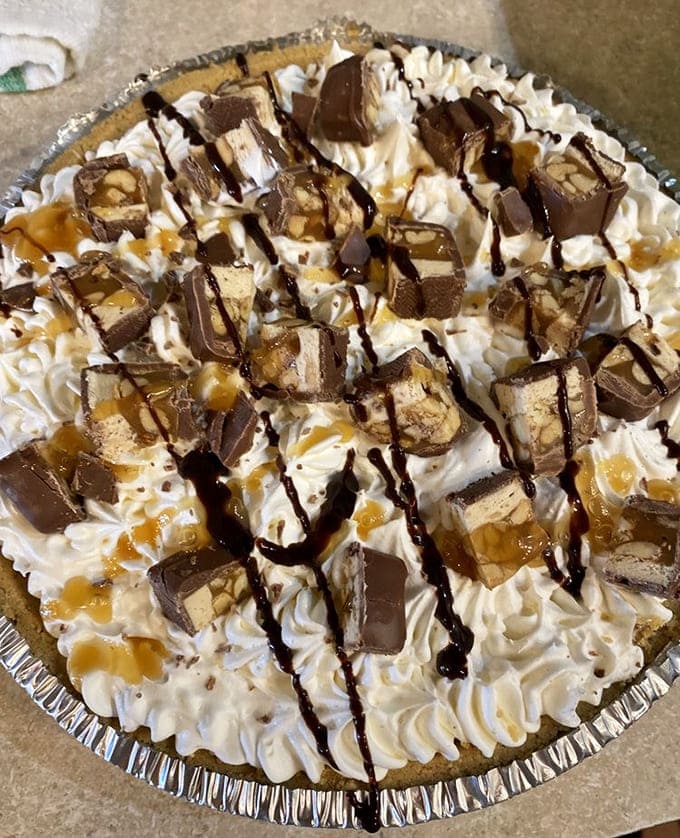 Snickers pie loaded with candy bar chunks, caramel drizzle, and whipped cream proves that sometimes more is definitely more.
