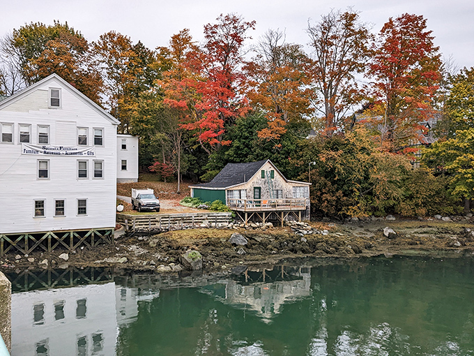 Weathered buildings hug the riverbank like old friends, their wooden facades telling stories of countless Maine winters survived.
