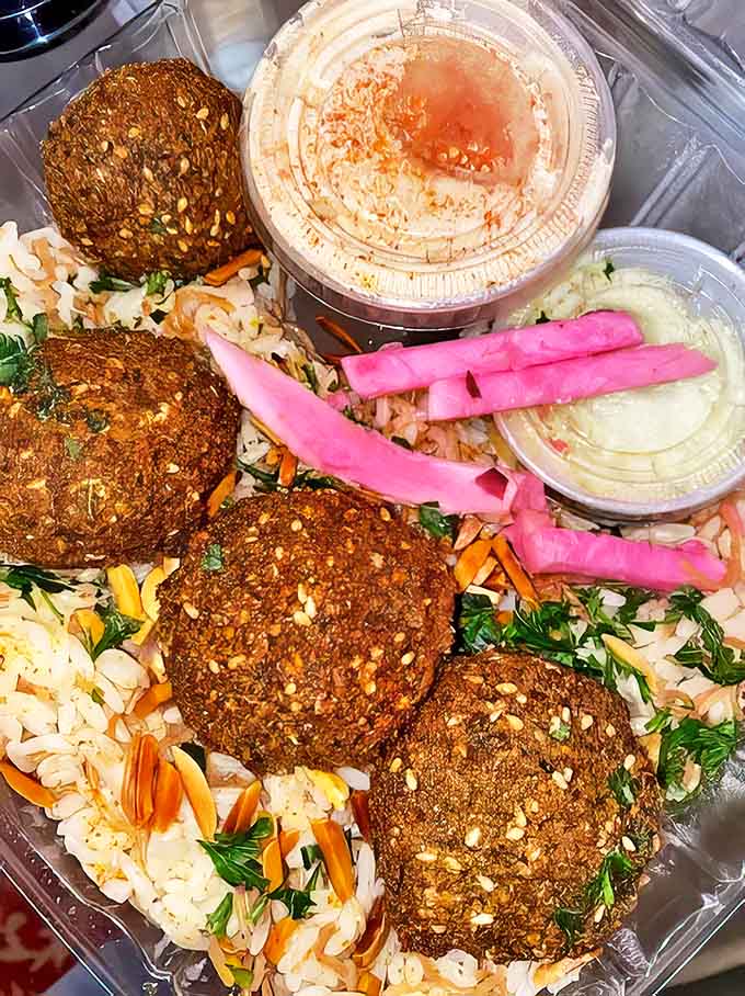 Golden-brown falafel balls nestled on aromatic rice with vibrant pickled turnips &ndash; a feast for both eyes and stomach.