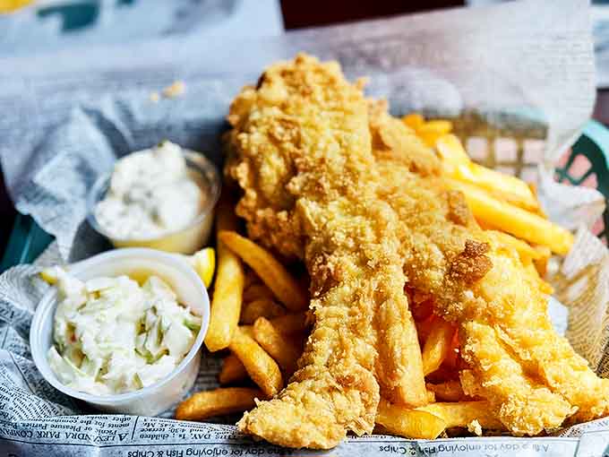 Golden-battered fish rests atop a generous portion of chips, the crispy exterior giving way to flaky, tender fish within.