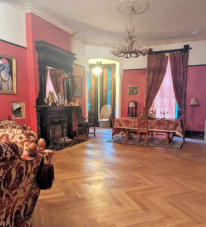 Rich crimson walls embrace antique furnishings in this formal room, where the antler chandelier adds unexpected rustic charm.