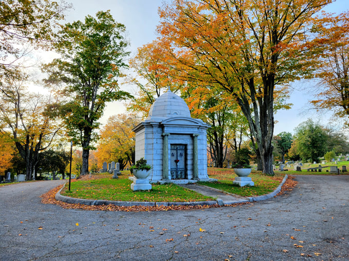 This elegant marble mausoleum stands like a miniature Greek temple, its classical columns framing a doorway to remembrance.