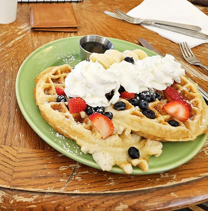 Behold the waffle that launched a thousand road trips! Golden, crispy exterior giving way to fluffy perfection, crowned with fresh berries and real Vermont maple syrup.
