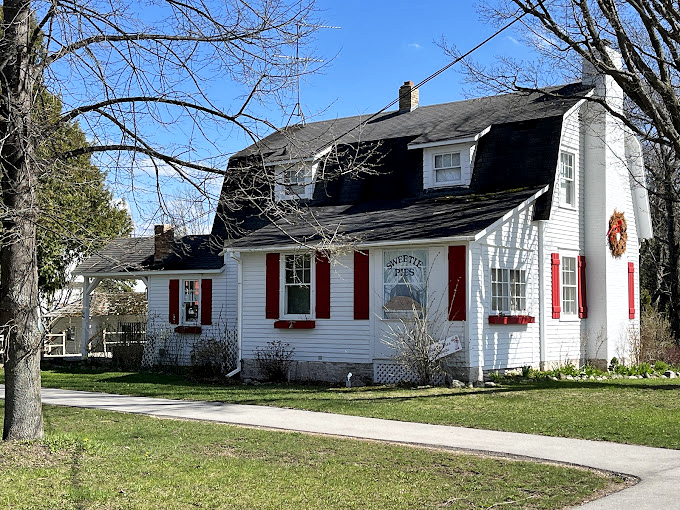 Adorable alert! This charming white cottage with red shutters looks like it jumped straight out of a fairy tale about the world's best baker.