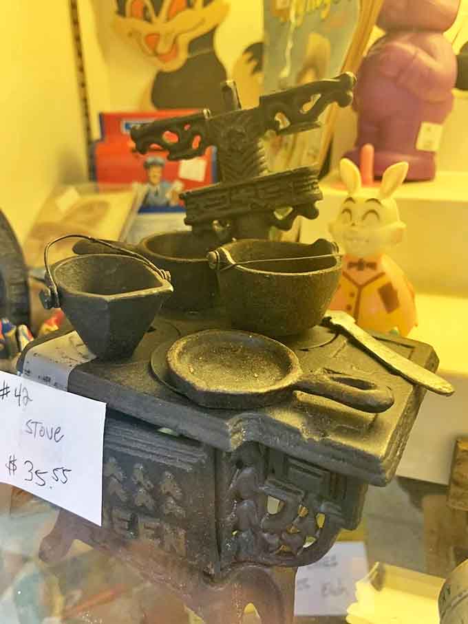 A miniature cast-iron stove complete with tiny pots reminds us that even dollhouses once required proper cooking equipment, because standards matter.