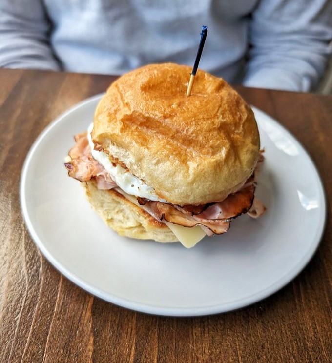 Breakfast sandwich perfection: a golden-brown bun cradling eggs, cheese, and ham. The kind of morning fuel that makes you forgive your alarm clock.