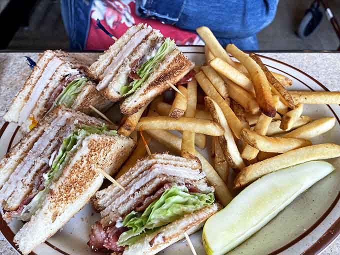 The club sandwich towers like a delicious skyscraper, stacked with layers of turkey, bacon, and veggies alongside a mountain of fries.
