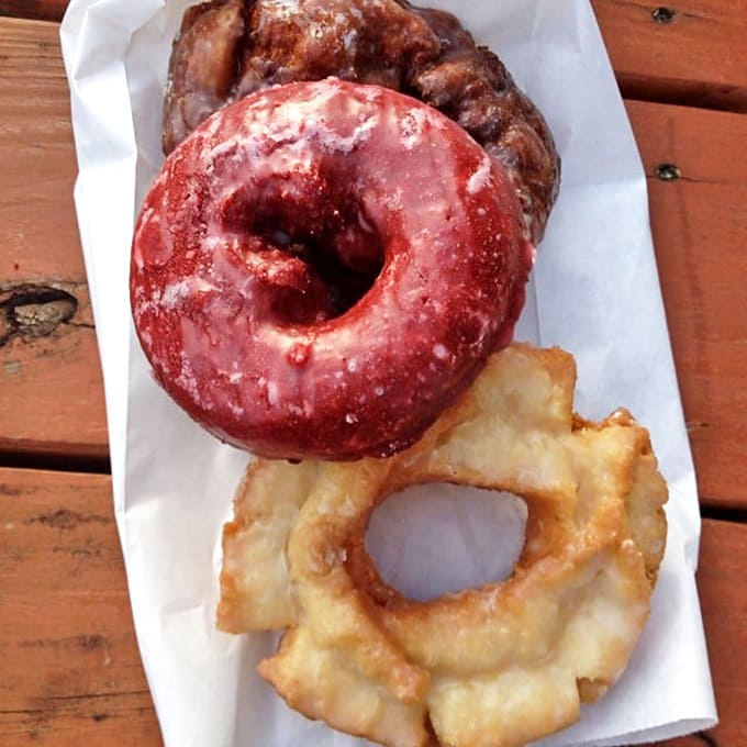 Assorted Donuts: The holy trinity of donut perfection &ndash; glazed, chocolate, and apple fritter &ndash; nestled together like old friends sharing sweet secrets.