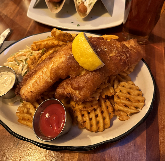 Beer-battered haddock that shatters at first bite, revealing steamy, flaky perfection beneath &ndash; paired with waffle fries that could start their own fan club.
