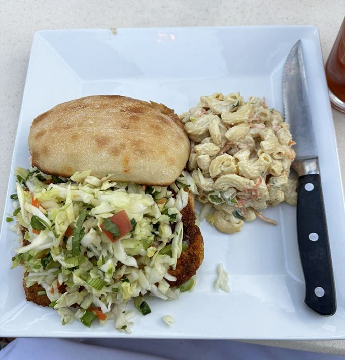 The fish sandwich arrives perfectly crisp, adorned with fresh slaw and paired with a creamy macaroni salad that would make any Hawaiian proud.