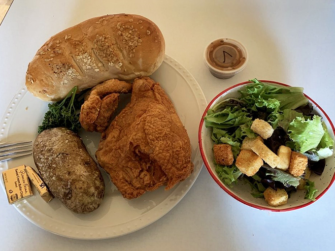 The classic country plate: crispy fried chicken, fluffy baked potato, and fresh-baked bread that would make any grandmother nod in approval.