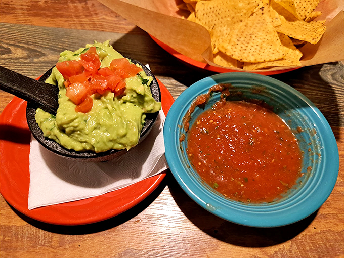 Fresh guacamole that's chunky, creamy, and topped with diced tomatoes - simple perfection in a traditional molcajete bowl.