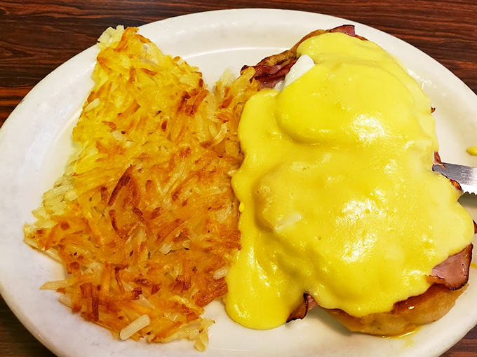 Eggs Benedict done right &ndash; hollandaise sauce cascading over perfectly poached eggs, with golden hash browns standing guard on the side.